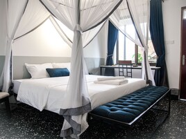 Quarto com cama de dossel, um banco, uma escrivaninha e uma cadeira.