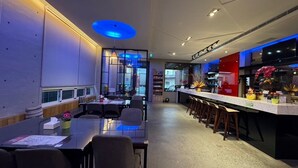 Um restaurante moderno com área de bar, opções de assentos e vista através de um painel de vidro.