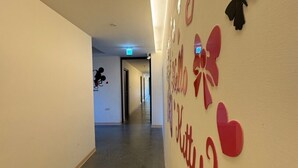 Um corredor com uma parede decorada com recortes de borboletas e o nome "Kutt" em letras vermelhas.