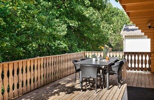 Um pátio externo com deck de madeira, uma mesa com cadeiras e um vaso de planta.