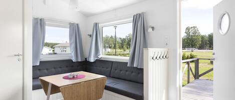 Quarto com área de assento embutida, uma pequena mesa e vista para o exterior pela janela.