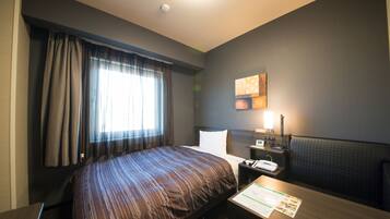 Quarto de hotel com uma cama grande, uma escrivaninha, uma mesa de cabeceira, uma luminária e um quadro na parede.