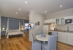 Um quarto com cama de dossel, mesa de cabeceira com abajur e televisão fixada na parede.