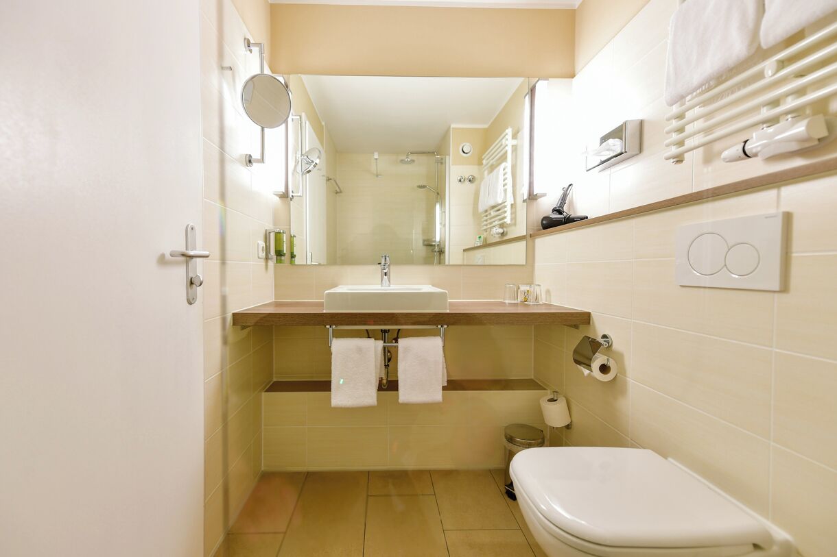 Casa de banho compacta com lavatório, espelho, porta-toalhas e sanita.