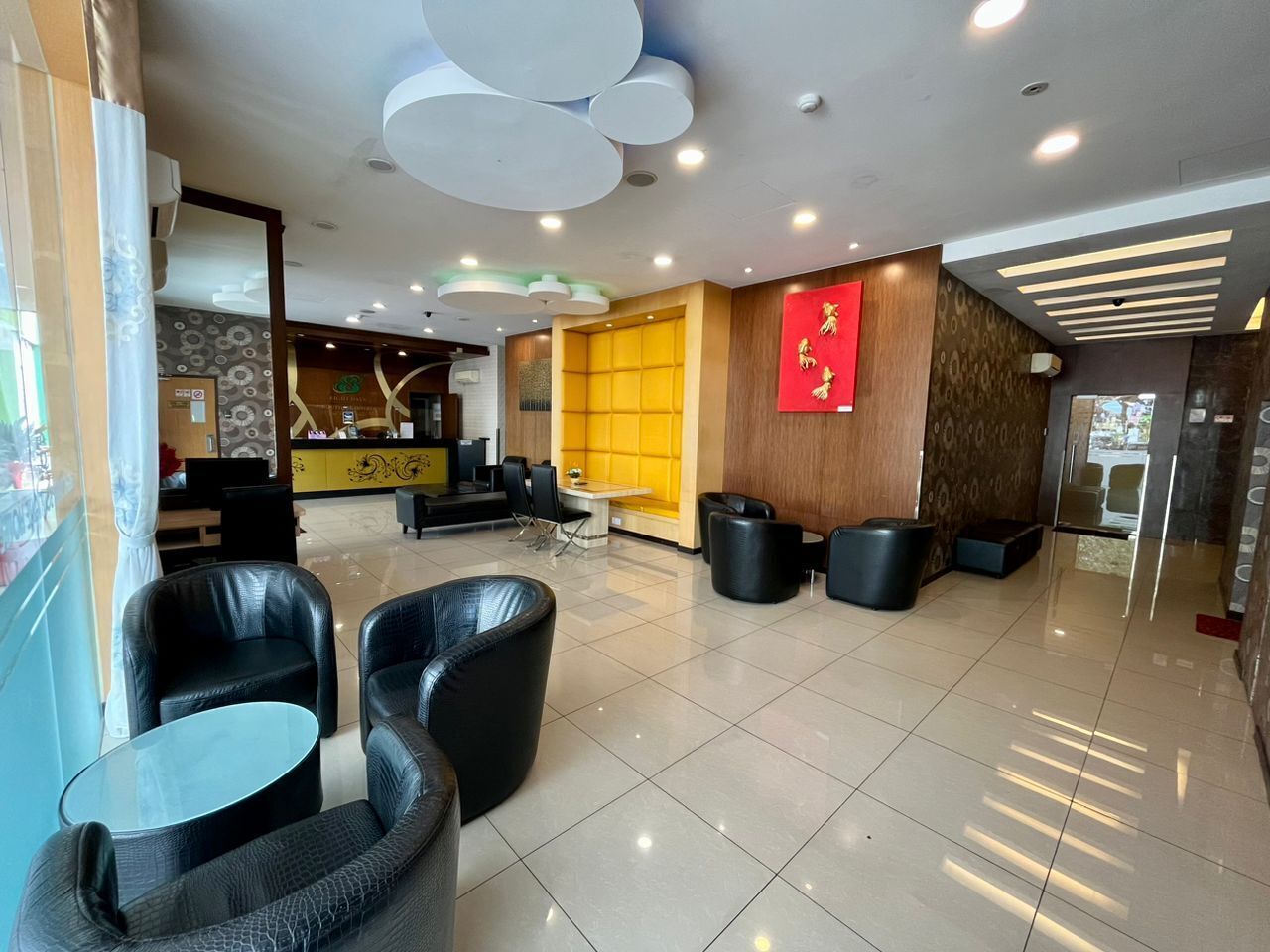 Um hall moderno com poltronas de couro preto, um balcão de recepção e uma parede com detalhes em amarelo.