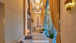 Um corredor luxuoso com um sofá macio, um candelabro e vista através de uma porta de vidro.