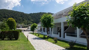 Uma trilha que conduz a uma fileira de edifícios modernos com grandes janelas e montanhas ao fundo.