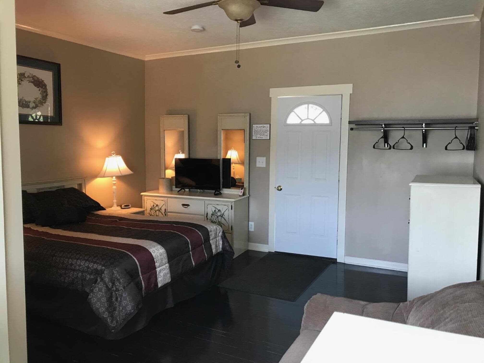 Quarto com cama, abajures, televisão, guarda-roupa e porta com espelho.