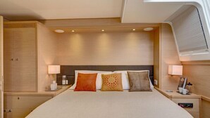 Quarto de hotel moderno com uma cama grande, cabeceira de madeira e mesas de cabeceira embutidas.
