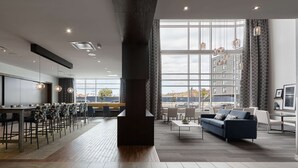 Interior moderno com área de refeições, um sofá e janelas amplas com vista para a cidade.