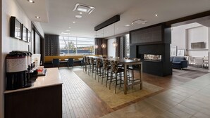 Uma área de bar moderna com máquina de café, assentos e lareira.