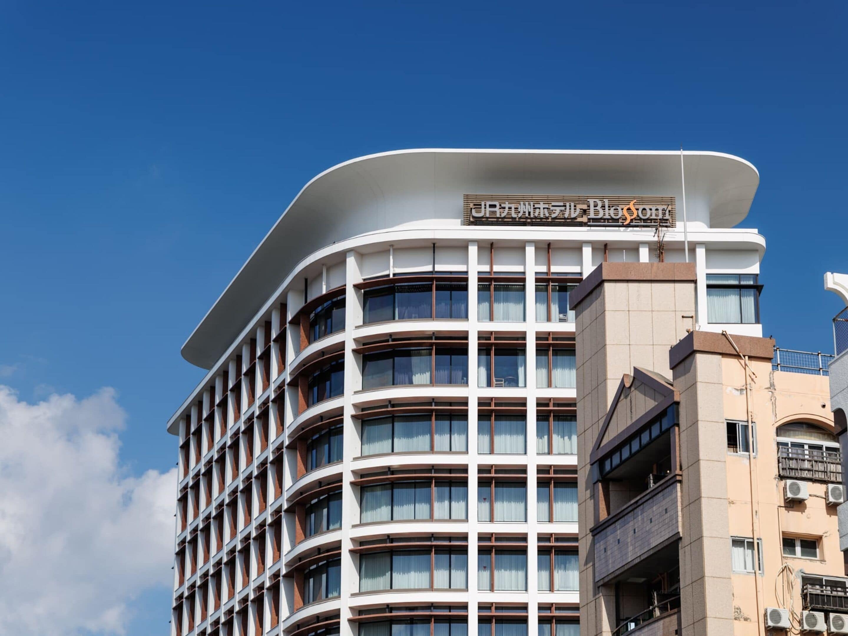 Um hotel moderno com fachada curva, várias varandas e um letreiro grande no topo.
