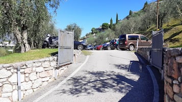 Uma área de estacionamento com muros de pedra, carros estacionados e árvores.