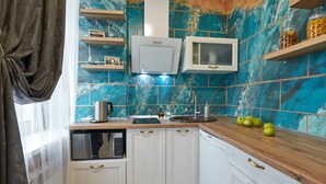 Cozinha com armários brancos, micro-ondas, pia e bancada de madeira.