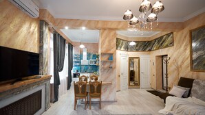 Uma sala de estar ampla com lareira, área de jantar com cadeiras, um sofá e uma televisão.