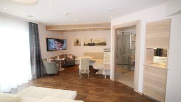 Uma sala de estar moderna com um sofá, uma televisão e um espaço de jantar com mesa e cadeiras.