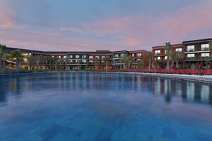 Um hotel com uma piscina grande, vários andares e um design arquitetônico moderno.
