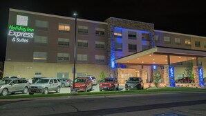 Um hotel Holiday Inn Express & Suites com fachada moderna, vários espaços de estacionamento e entrada bem iluminada.