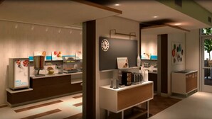 Uma área de recepção moderna com um quiosque de autoatendimento, um relógio e uma estação de café.