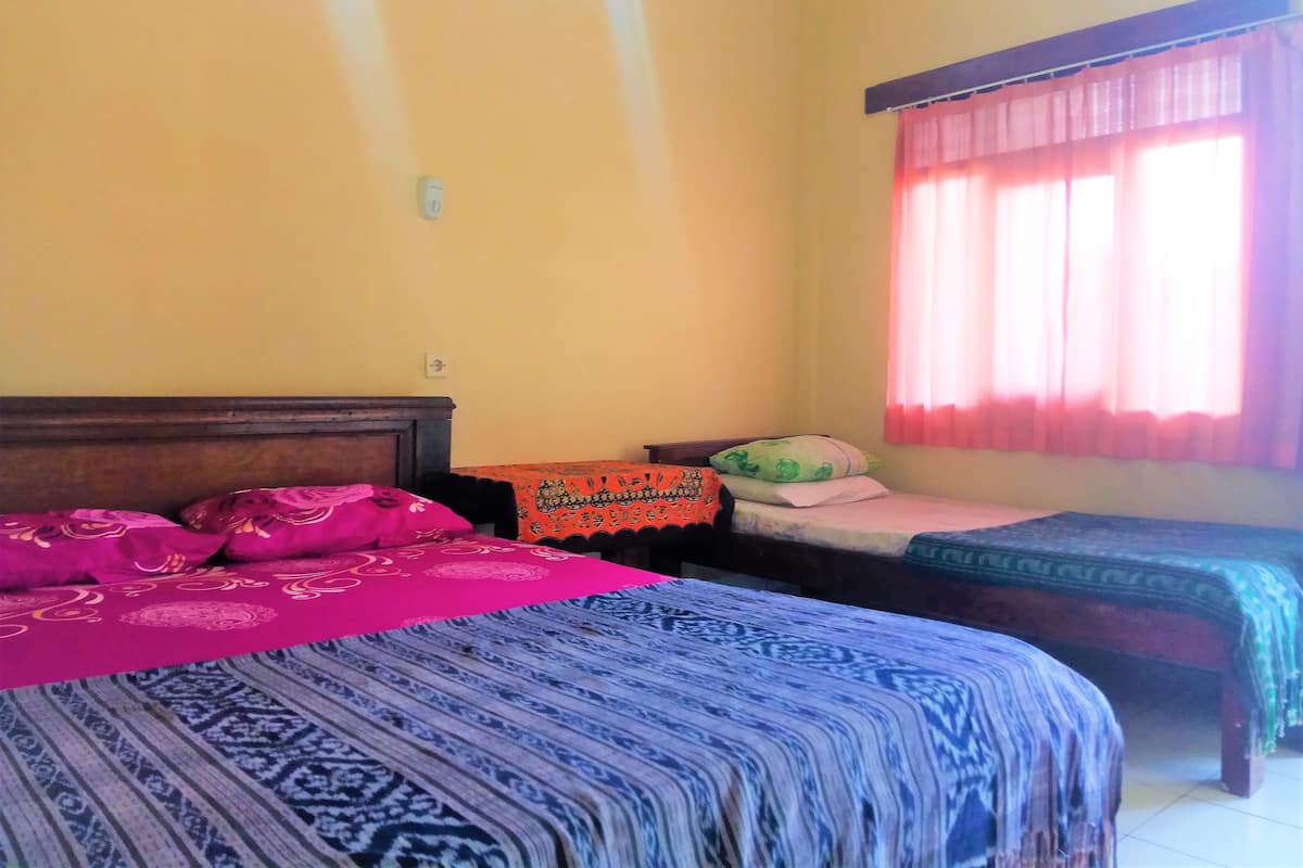 Quarto com duas camas, cabeceira de madeira, janela com cortinas cor de rosa e luminária fixada na parede.