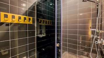 Uma casa de banho moderna com cabine de duche em vidro, um porta-toalhas amarelo e um chuveiro manual.