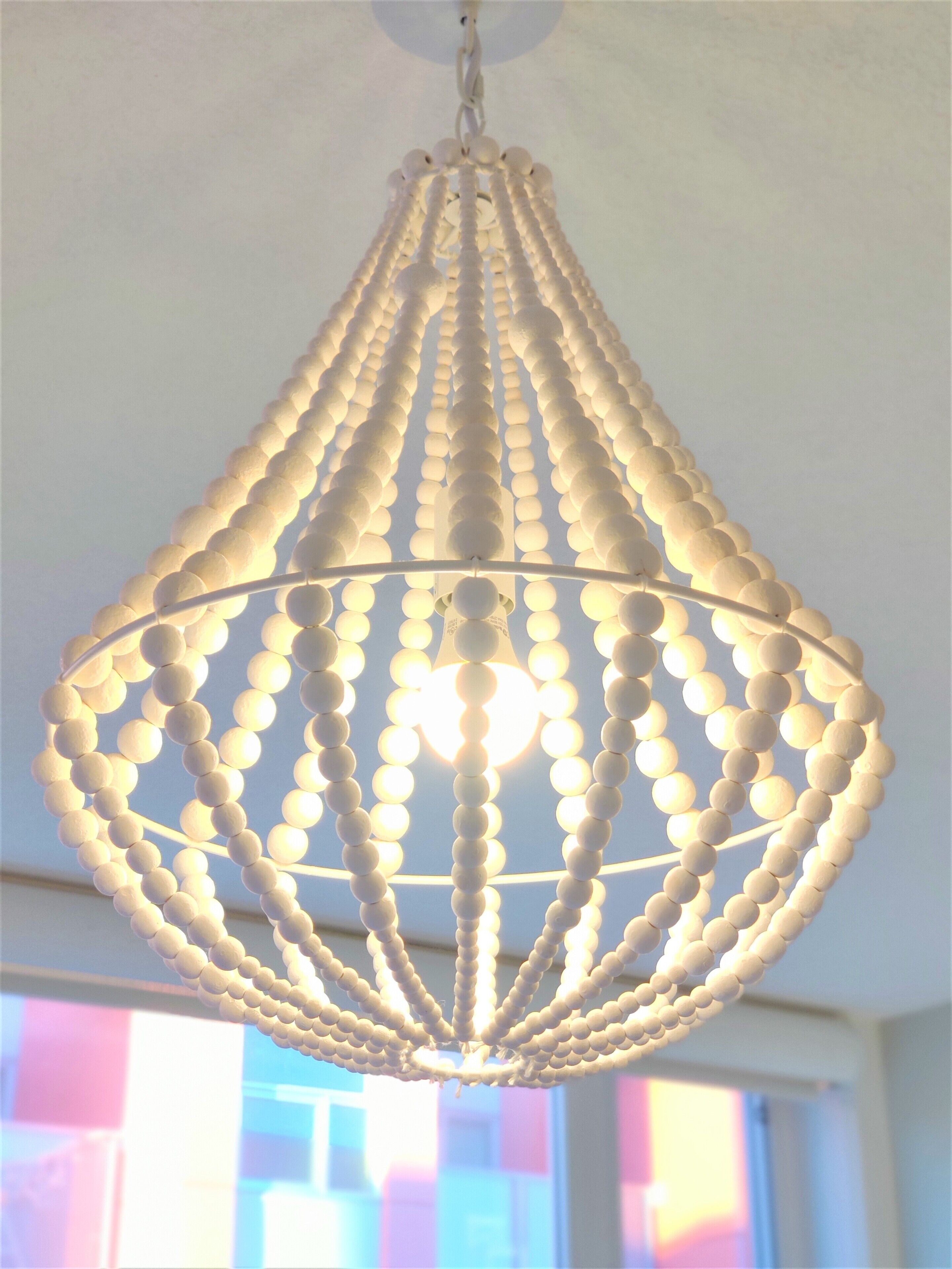 Um candelabro com vários níveis de lâmpadas esféricas, pendurado em um acessório branco no teto.