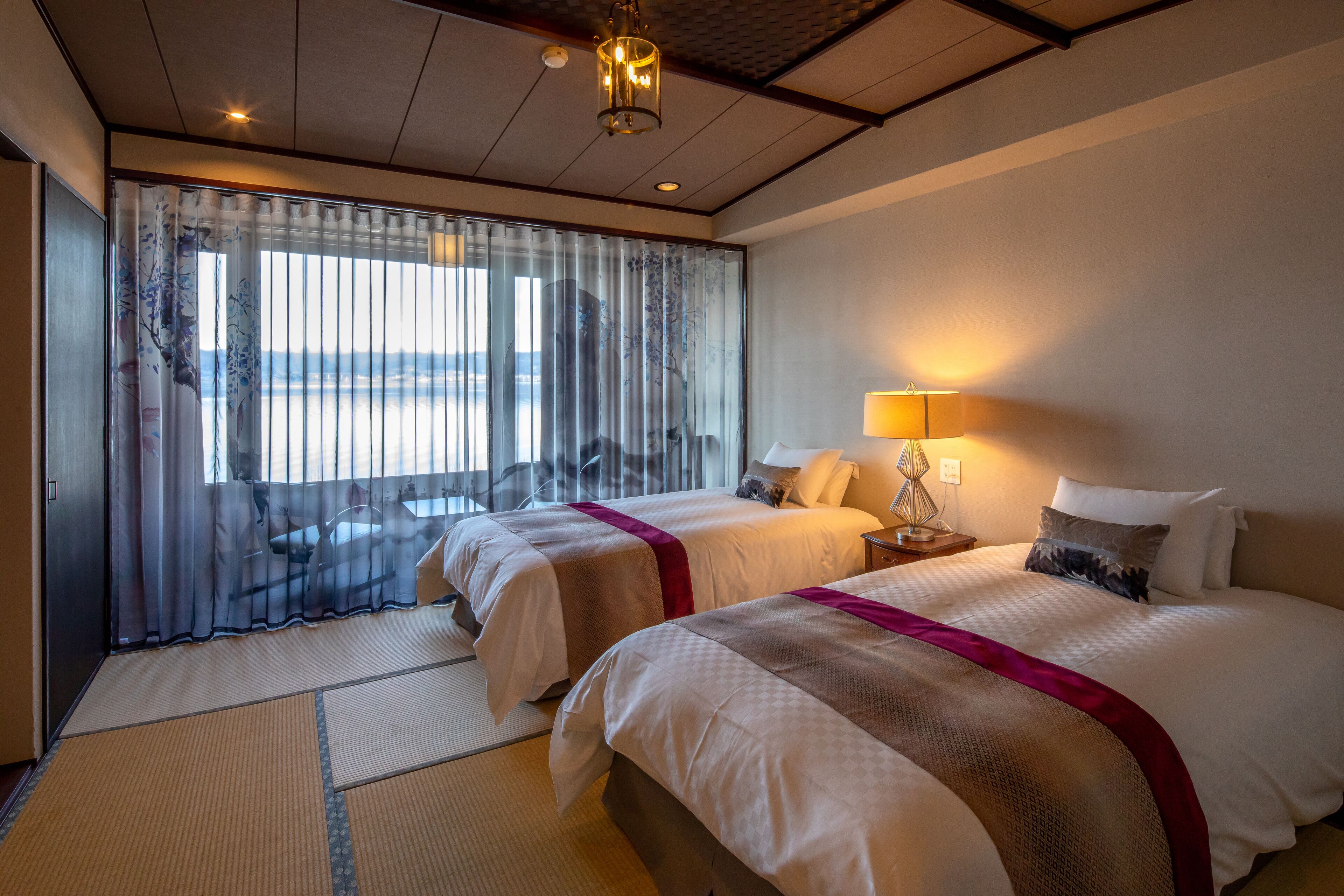 Quarto de hotel com duas camas, vista para o mar e decoração em estilo tradicional japonês.