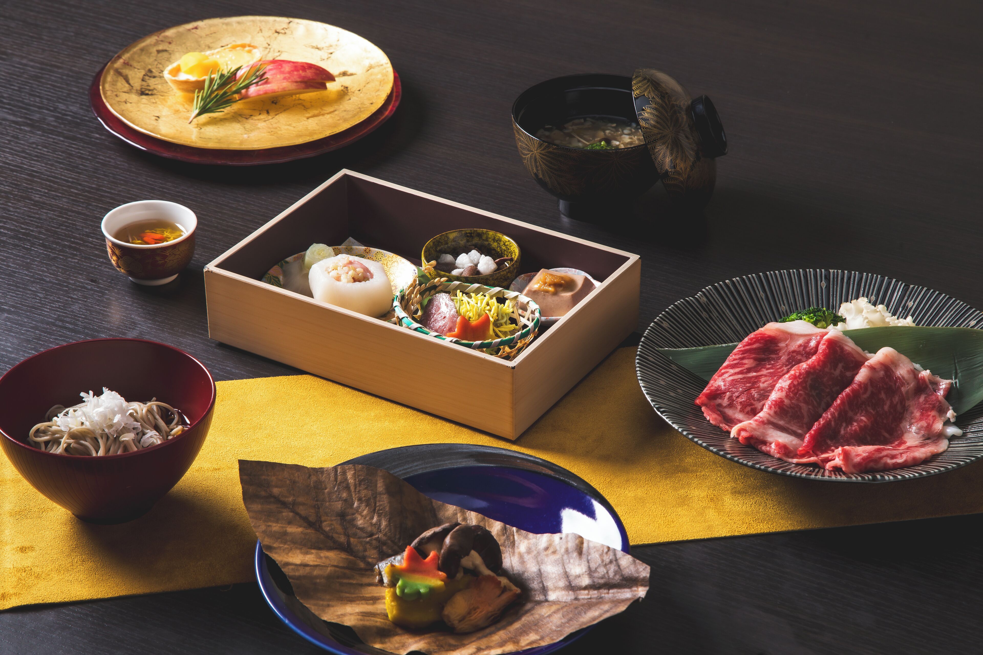 Uma refeição tradicional japonesa com diversos pratos e uma caixa de madeira com alimentos.