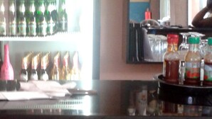 Uma área de bar com prateleiras de garrafas e copos.