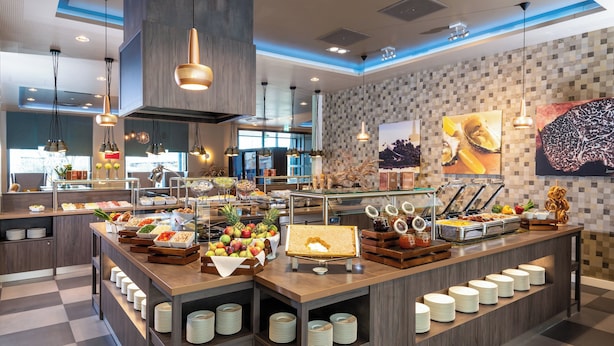 Uma área de buffet com diversas opções de comida, incluindo frutas, vegetais e pratos prontos.