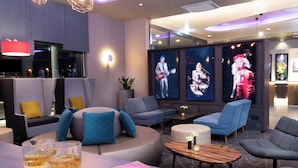 Uma área de estar moderna com sofás, uma mesa de centro e um bar com copos de bebida.