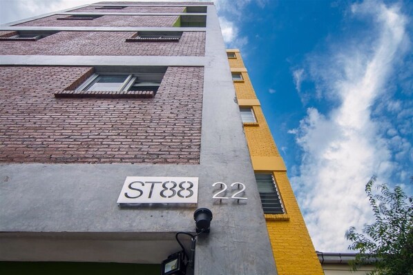 Um edifício com fachada de tijolos e uma seção amarela. O endereço ST88 22 está visível.