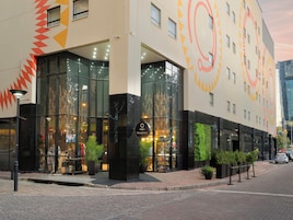 Um hotel com fachada de vidro moderna, área de recepção e um amplo espaço de estar ao ar livre.