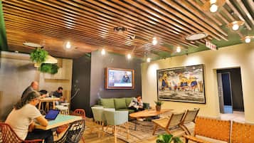 Um interior moderno com tetos de ripas de madeira, áreas de estar e uma tela de televisão.