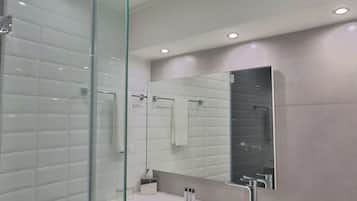 Casa de banho moderna com cabine de duche em vidro, lavatório branco e sanita.