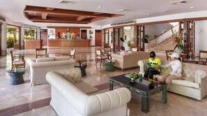 Um hall amplo com balcão de atendimento, assentos confortáveis e escadaria para os andares superiores.