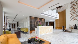 Um hall moderno com balcão de recepção, área de estar e um painel decorativo.