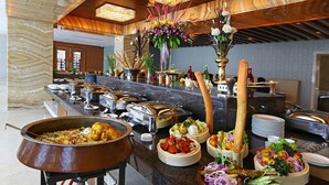 Um buffet com diversos pratos, incluindo uma grande panela de arroz, saladas em tigelas e outras opções variadas.