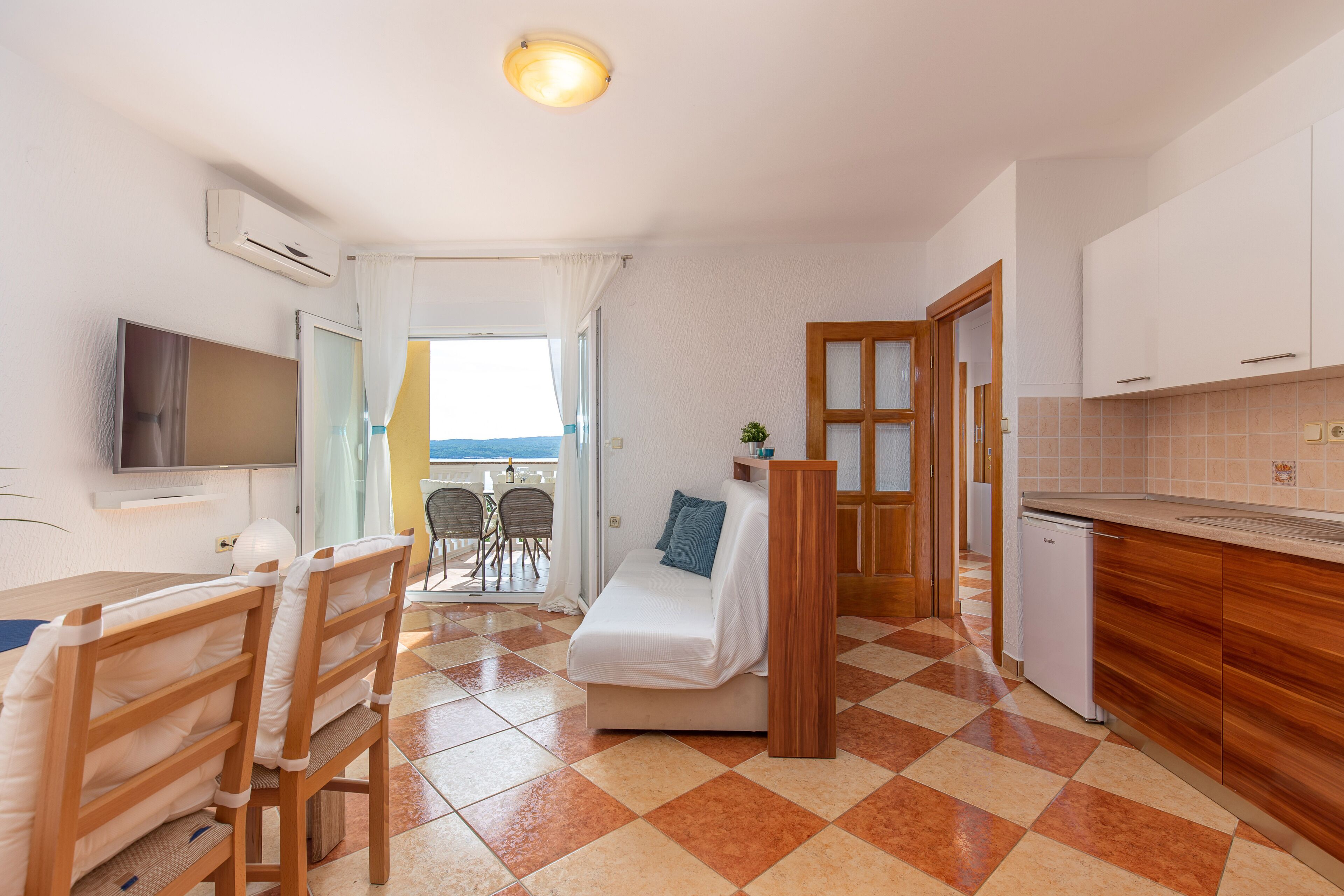 Um espaço compacto com cozinha compacta, área de refeições e sofá.