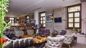 Uma área de estar acolhedora com assentos confortáveis, uma mesa de centro de madeira e uma estante repleta de livros.
