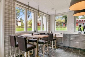 Cozinha moderna com área de jantar, janelas amplas e vista para o exterior.