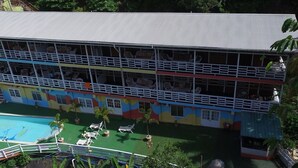 Um edifício com vários andares, varandas, piscina e uma pequena área de recreação.