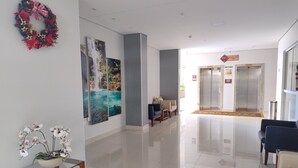 Um lobby moderno com uma mesa de centro de vidro, uma grinalda decorativa e uma grande pintura com tema de cachoeira.