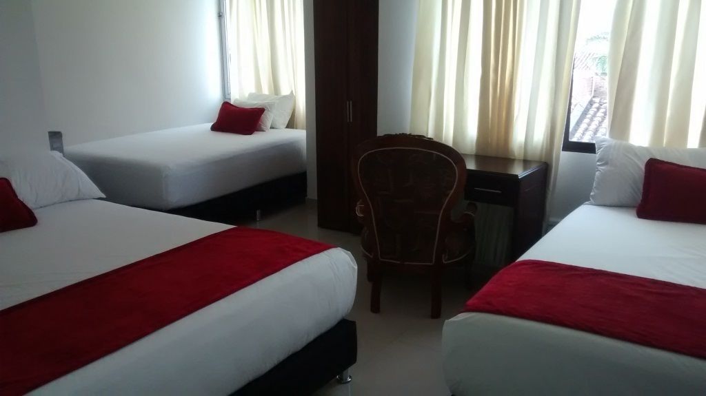 Quarto de hotel com duas camas, uma escrivaninha e uma cadeira.