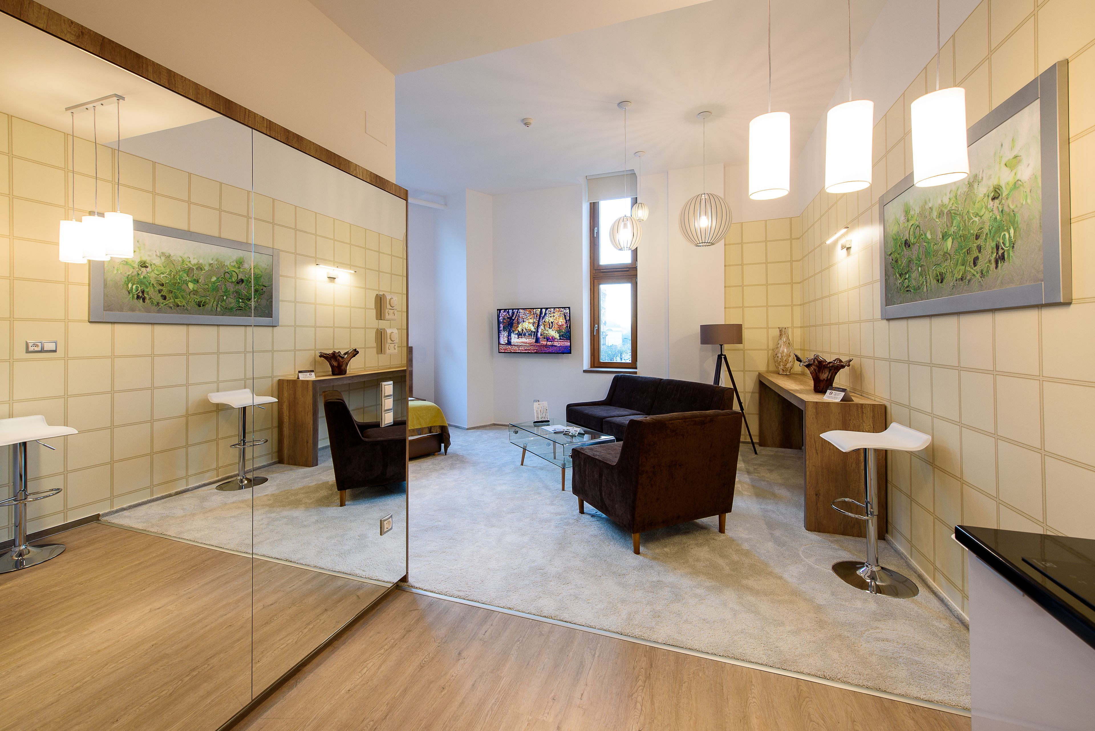 Um hall de hotel moderno com um sofá, cadeiras, uma mesa de centro e uma televisão.