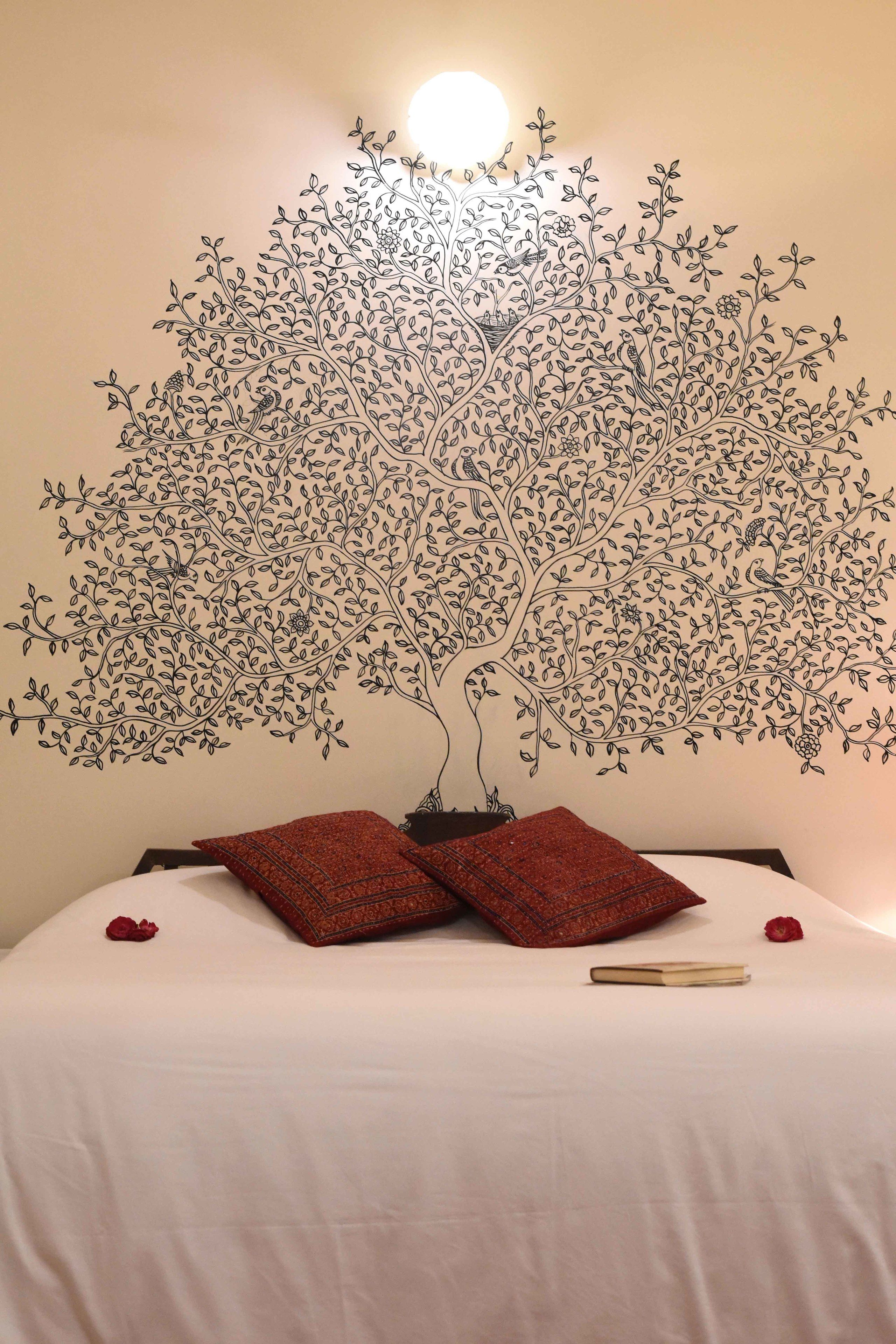 Cama com lençol branco, duas almofadas vermelhas e uma única rosa vermelha sobre a cama.