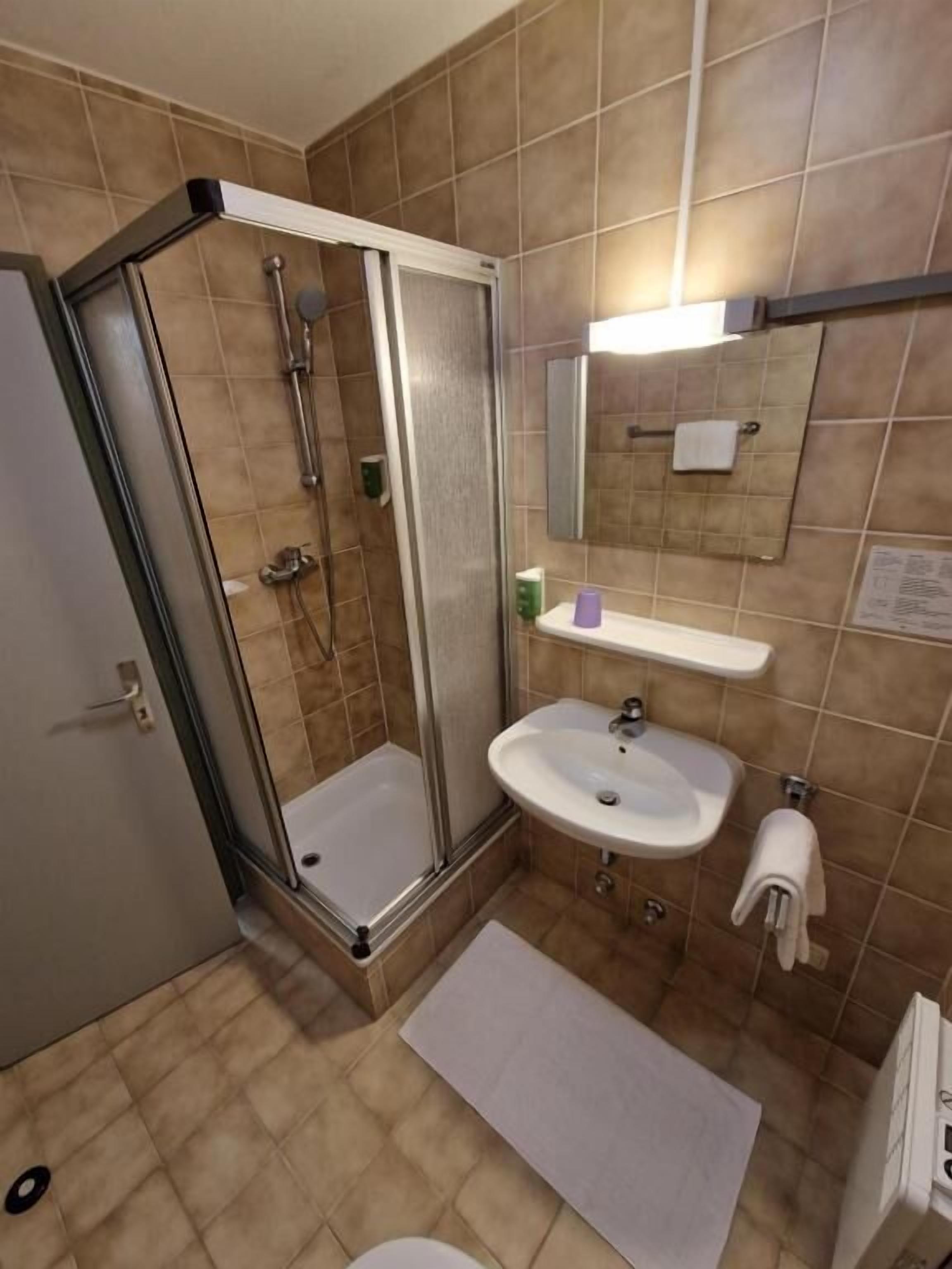 Casa de banho com cabine de duche, lavatório e espelho.