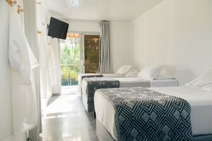 Quarto de hotel com duas camas, televisão e varanda com vista para áreas verdes.