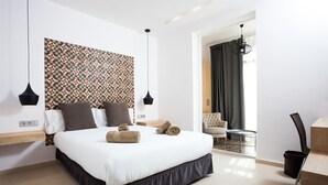 Quarto de hotel moderno com uma cama grande, um papel de parede estampado, uma escrivaninha e uma cadeira.