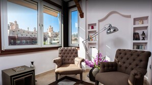 Uma sala de estar com dois poltronas marrons, uma mesa lateral, um abajur e uma estante.